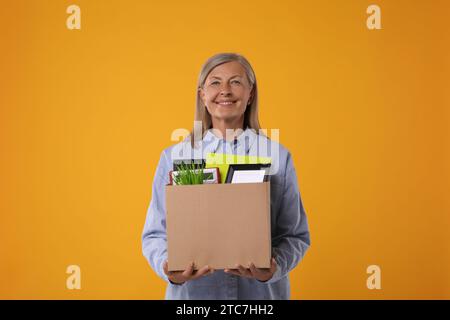 Happy unemployed senior woman with box of personal office belongings on ...