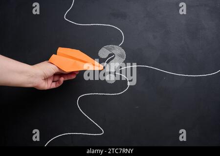 A hand holds a paper airplane with various trajectories marked by ...