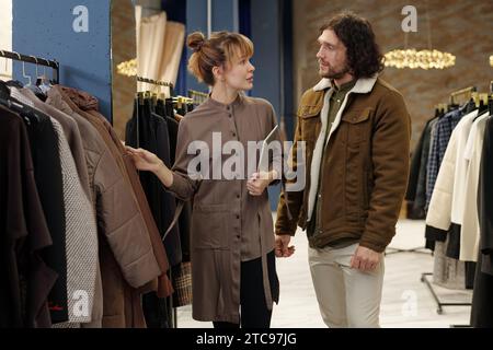 Adult woman buyer choosing warm plaid coat in clothing store Stock ...