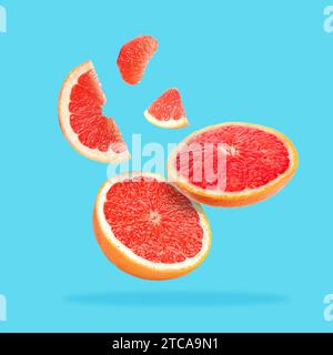 Pieces of grapefruit falling on light blue background Stock Photo - Alamy