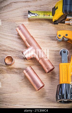 Copper water pipe cutter fittings tape measure on wood board top view ...