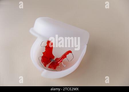 Red retainer or jaw expander on the background. Crooked teeth ...