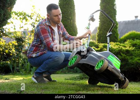 Man with screwdriver fixing lawn mower in garden, closeup Stock Photo ...