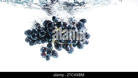 Bunch of red grapes splashing into crystal clear water on withe ...