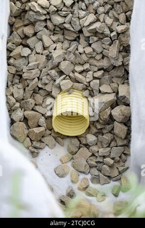 Yellow corrugated pipe with perforation in a trench with crushed stone ...