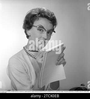 1950s historical, young woman working at a desk, writing notes in a ...