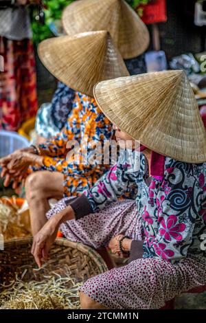 Women wearing Asian conical straw hats in a rice paddy field planting ...