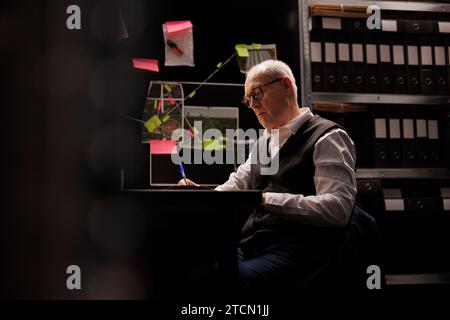 Overworked old investigator analyzing criminology report, working late ...