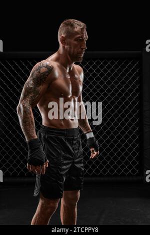 Conceptual image of a kickboxer. A real fighter stands in the real cage ...