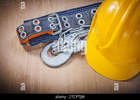 Construction body belt with metal carabiners chain hard hat on wooden ...