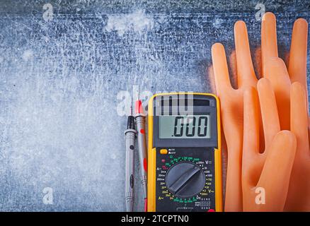 Digital multimeter dielectric rubber gloves on metallic background ...