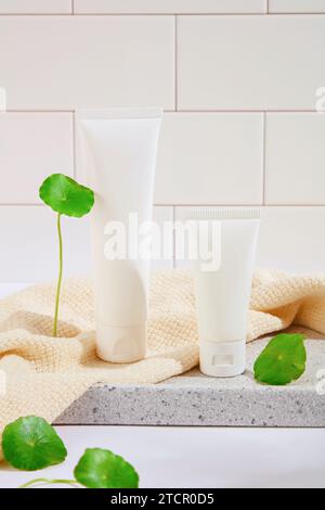 Close-up of two unlabeled cosmetic tubes placed on a sandy background ...