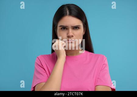 Portrait of resentful woman on light blue background Stock Photo - Alamy