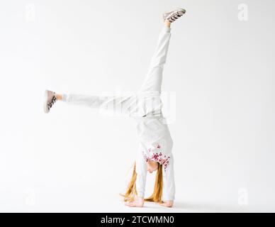 Cute little gymnast doing handstand on white background Stock Photo - Alamy