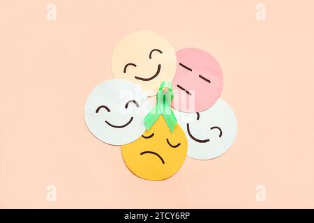 Paper faces with different emotions and green awareness ribbon on blue ...