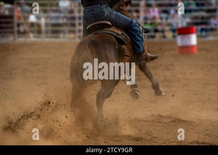 A barrel rider navigates the barrels on her horse during a rodeo event ...