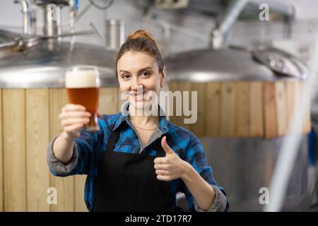 Portrait of female brewer who is standing with glass of beer on his ...