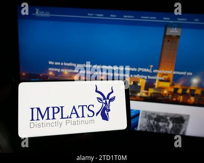 Mobile phone with website of company Impala Platinum Holdings Limited (Implats) in front of ...