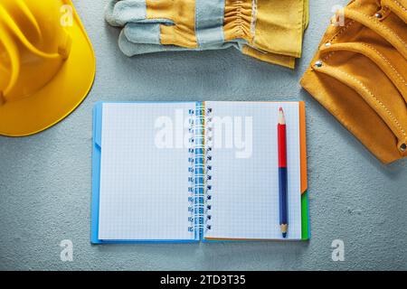 Safety gloves hard hat notepad pencil tool belt on concrete background ...