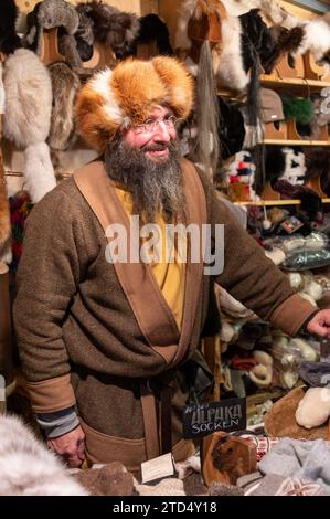 A reindeer fur trader selling fur goods in his wooden stall at the ...