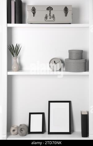 White shelves with clock, photo frames and different decor indoors ...