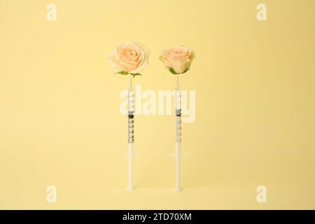 Medical syringes and rose flowers on pale yellow background Stock Photo ...
