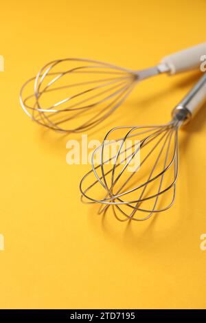 Two metal whisks on yellow background, closeup. Kitchen tool Stock ...