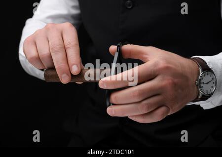 Man cutting tip of cigar on black background, closeup Stock Photo - Alamy