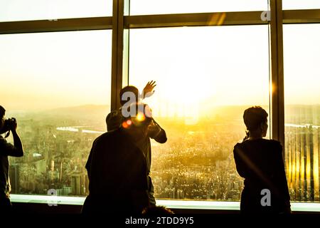 Tourists look through the windows at the skyline of Taipei, Taiwan ...
