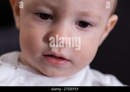 Face of a smiling baby boy with snot from his nose. Runny nose and ...