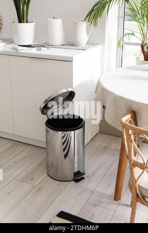 Opened metallic trash bin near table in interior of modern kitchen ...