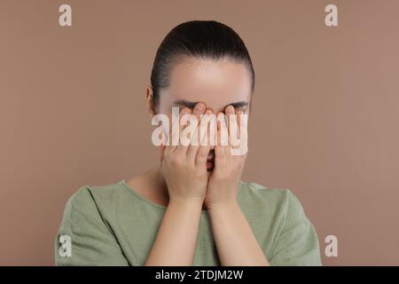 Resentful woman covering face with hands on light blue background Stock ...