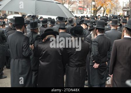 A crowd of Hasidic jewish mourners listen to eulogies at the funeral ...