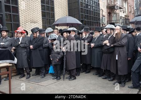 A crowd of Hasidic jewish mourners listen to eulogies at the funeral ...