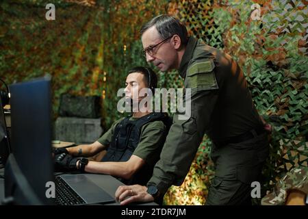 Young serious officer of command and control center in military uniform ...
