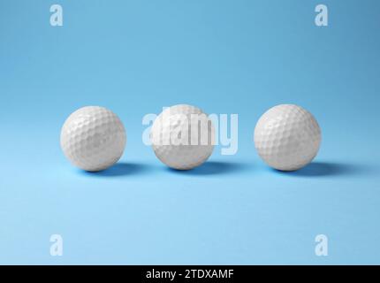 Three golf balls on light blue background, flat lay. Space for text ...