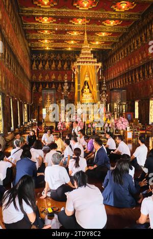 A group of worshippers, busy praying. Inside the red, richly decorated ...