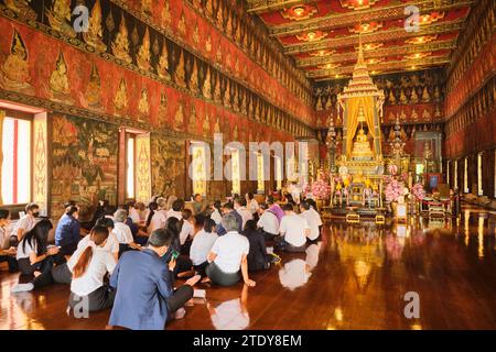 A group of worshippers, busy praying. Inside the red, richly decorated ...