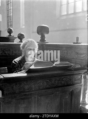 Sexton woman with bible in church pew in the Grote Kerk in Edam ca ...
