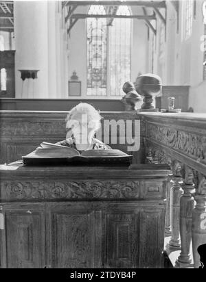 Sexton woman with bible in church pew in the Grote Kerk in Edam ca ...