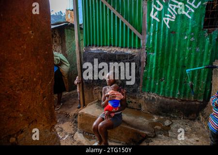 A woman and her child are seaated outside the neighborhoods in Kibera ...