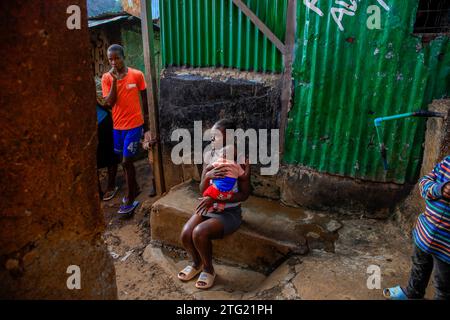 A woman and her child are seaated outside the neighborhoods in Kibera ...