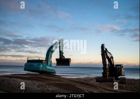 Maintenance diggers Bournemouth beach arranging sand around new ...