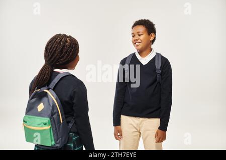 cheerful african american schoolkids with backpacks standing and ...
