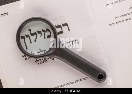 One magnifying lens on a Hebrew dictionary page, macro, top view. "The ...
