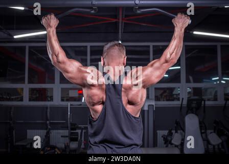 Image of a powerful athlete doing a pull-up in the gym. Back pumping ...