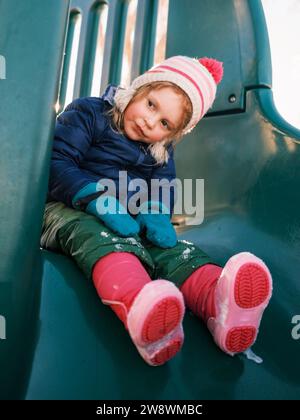 Child in red hat playing in snow on Christmas vacation. Winter outdoor ...