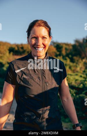 Portrait of smiling female coach standing with exercise mat against ...