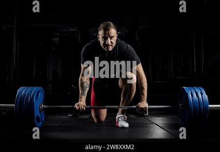 Professional athlete bent over the barbell and is preparing to lift a ...