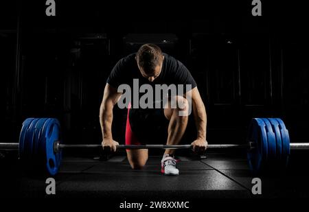 Professional athlete bent over the barbell and is preparing to lift a ...